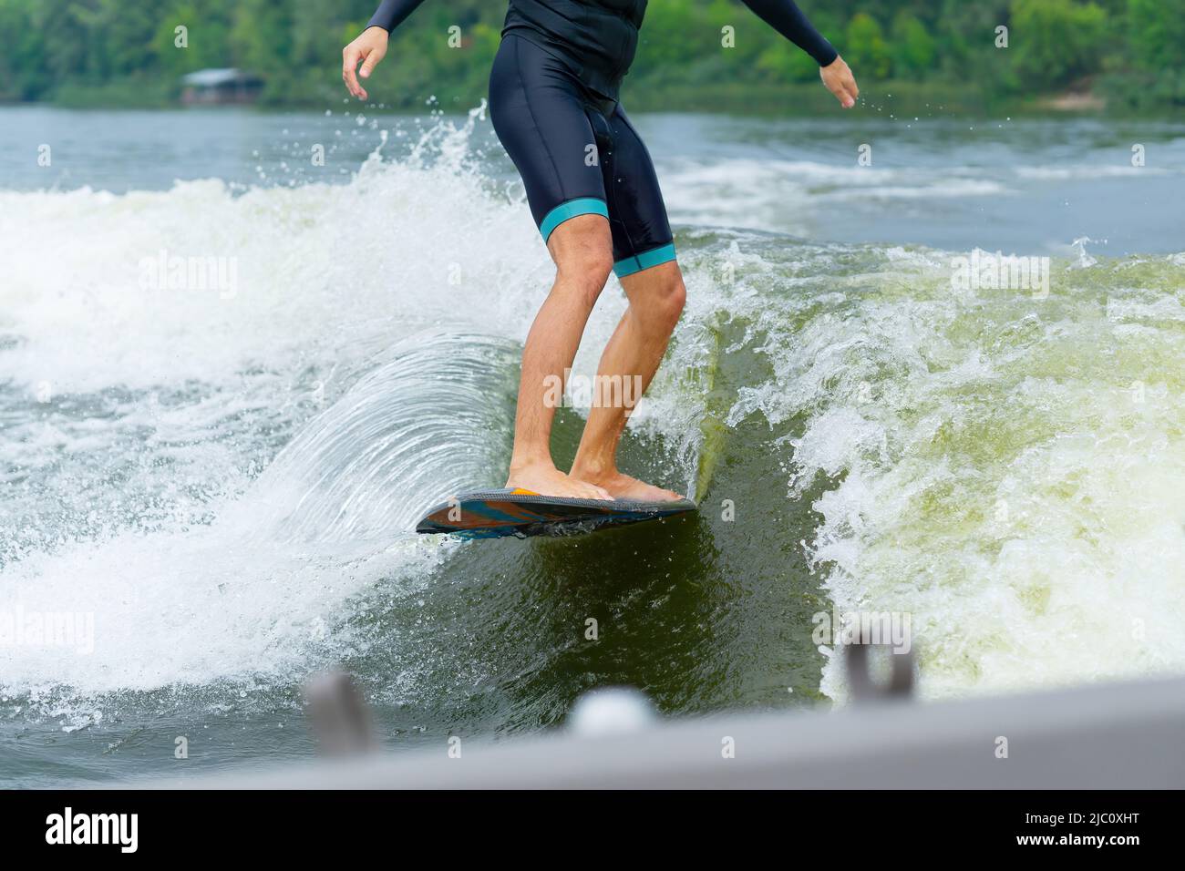 Crop view of a wakeboarder riding a wave on the river Stock Photo - Alamy