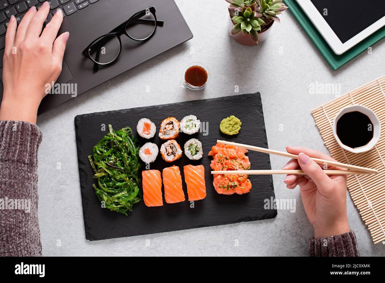 Woman eating sushi takeaway at work desk overhead. Eating sushi for ...