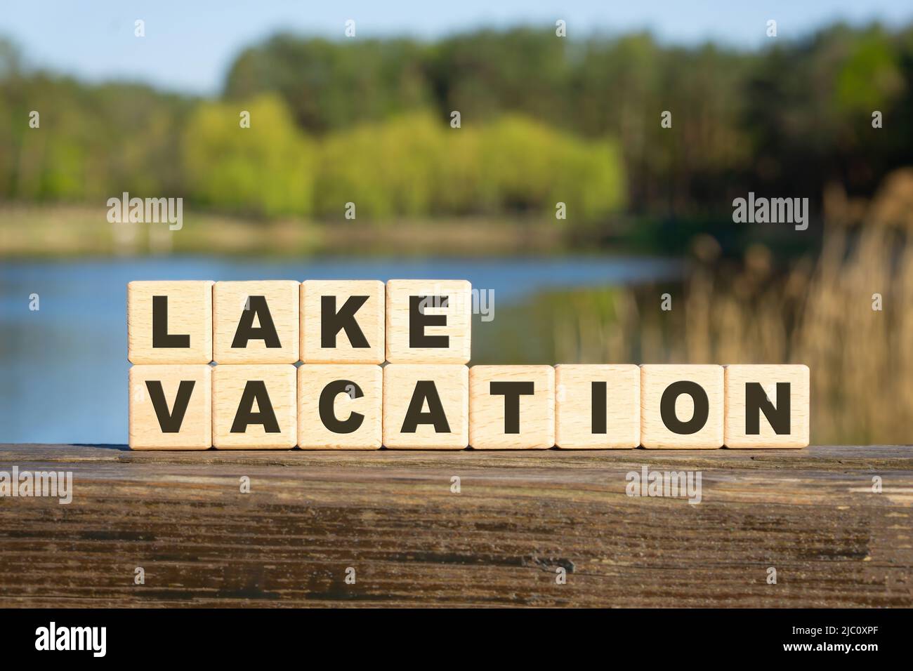 Text LAKE VACATION made from wooden alphabet blocks against a nature ...