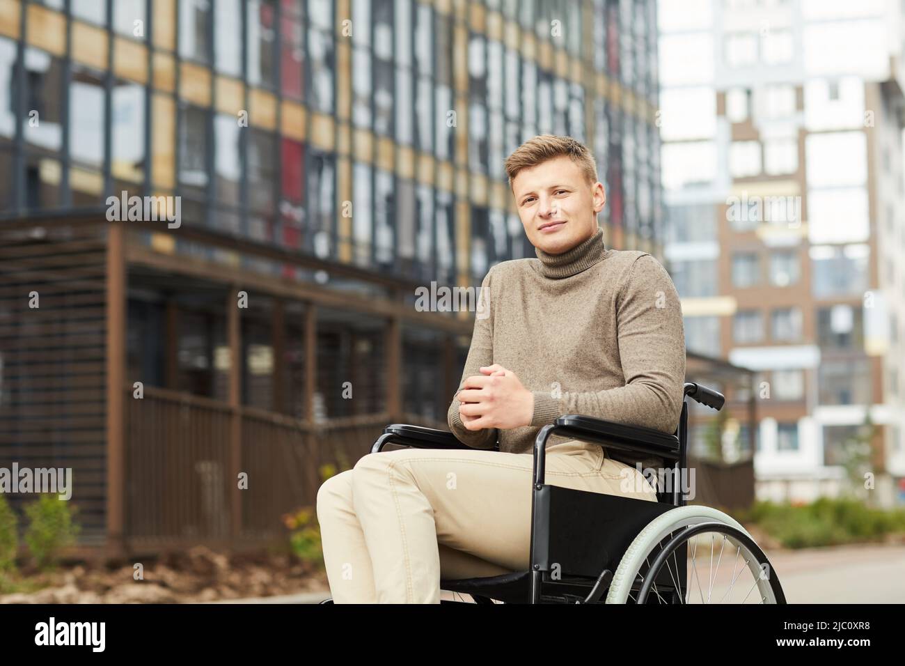 Portrait of serious handsome young man with disability sitting in ...