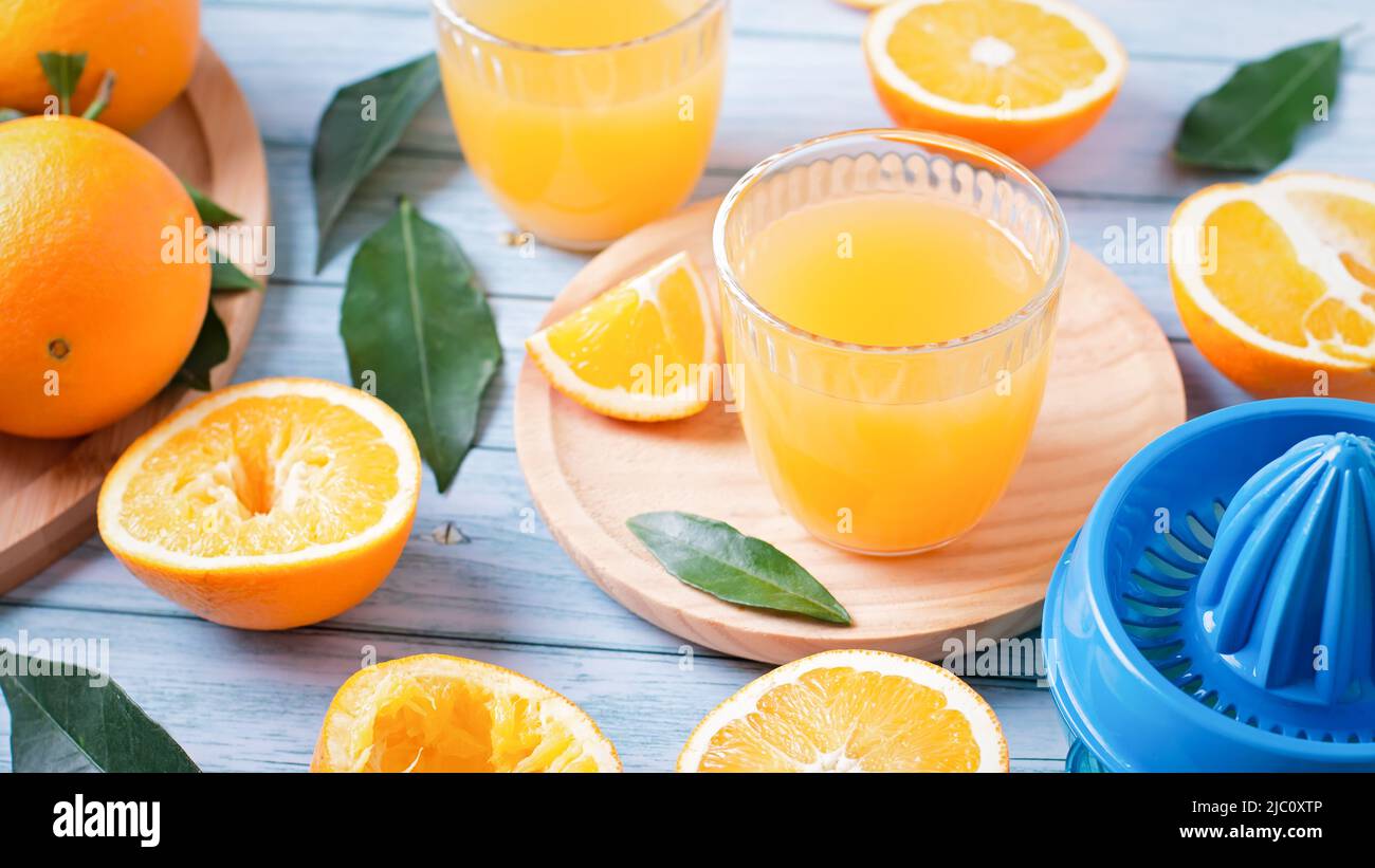 Fruit squeezer and ripe fresh oranges on blue wooden table top, fresh ...