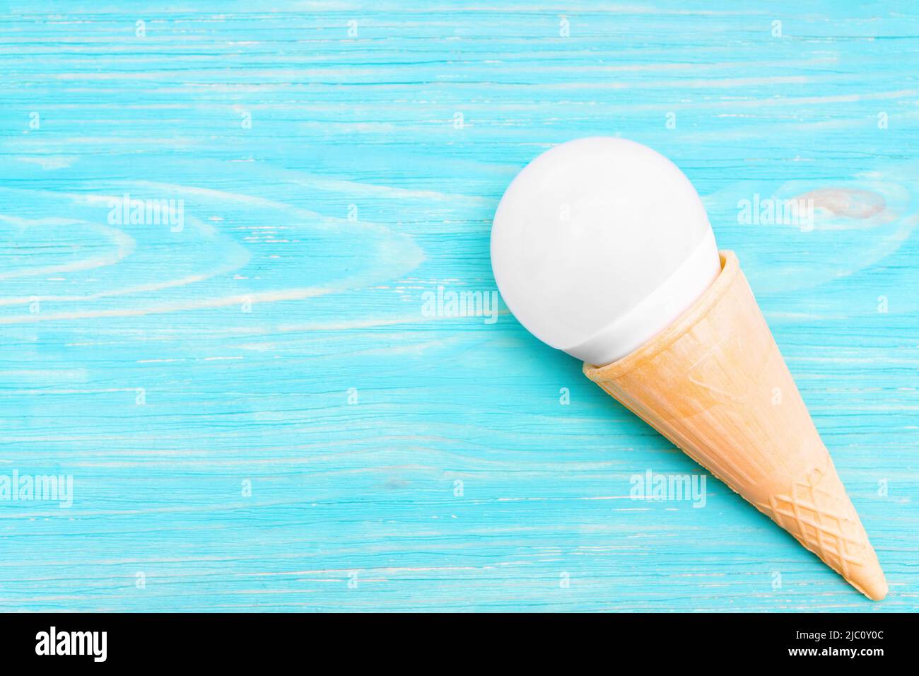 LED light bulb in a waffle ice cream cone on a blue wooden background ...
