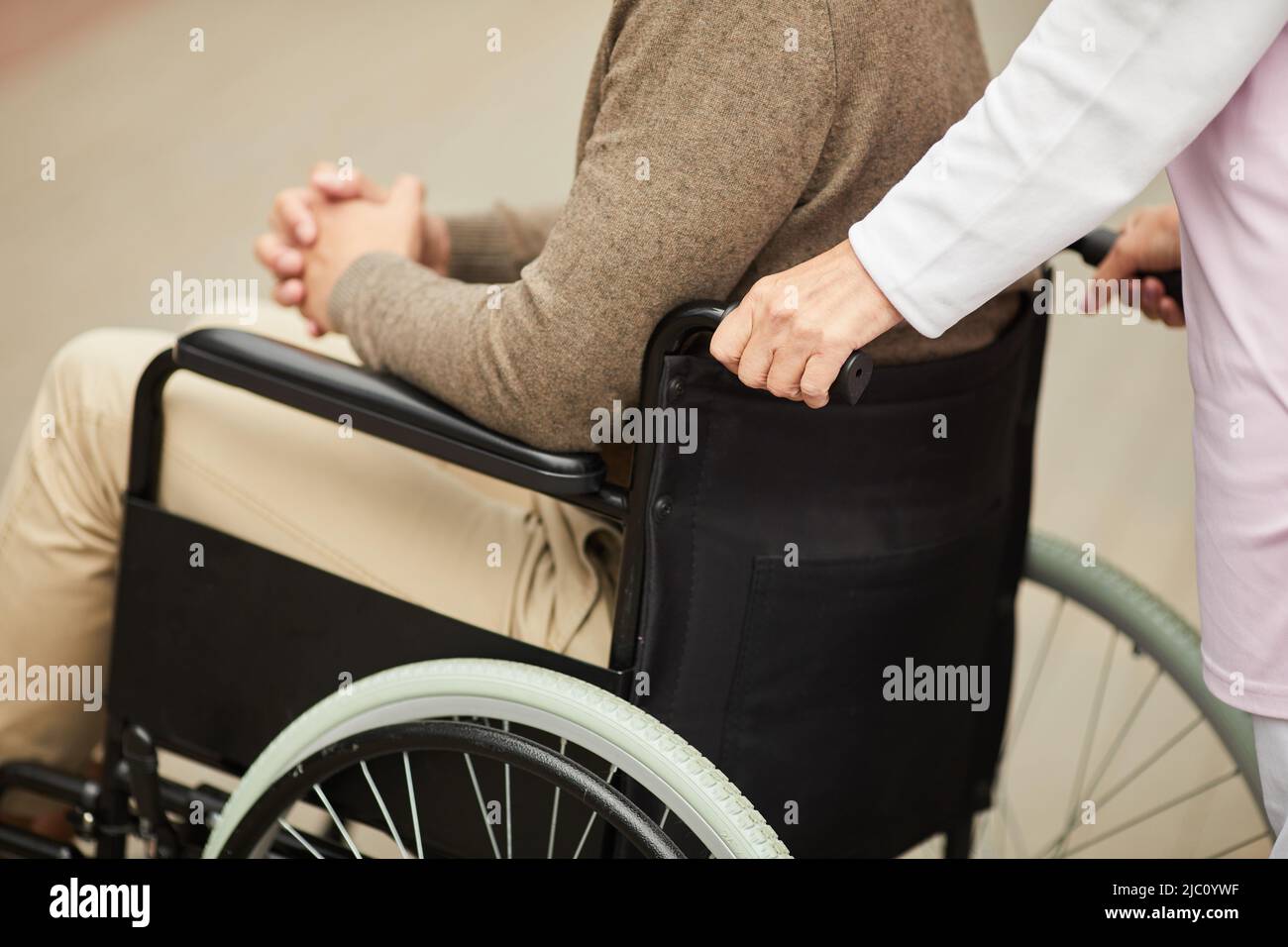 Close-up of unrecognizable medical nurse pushing wheelchair with ...