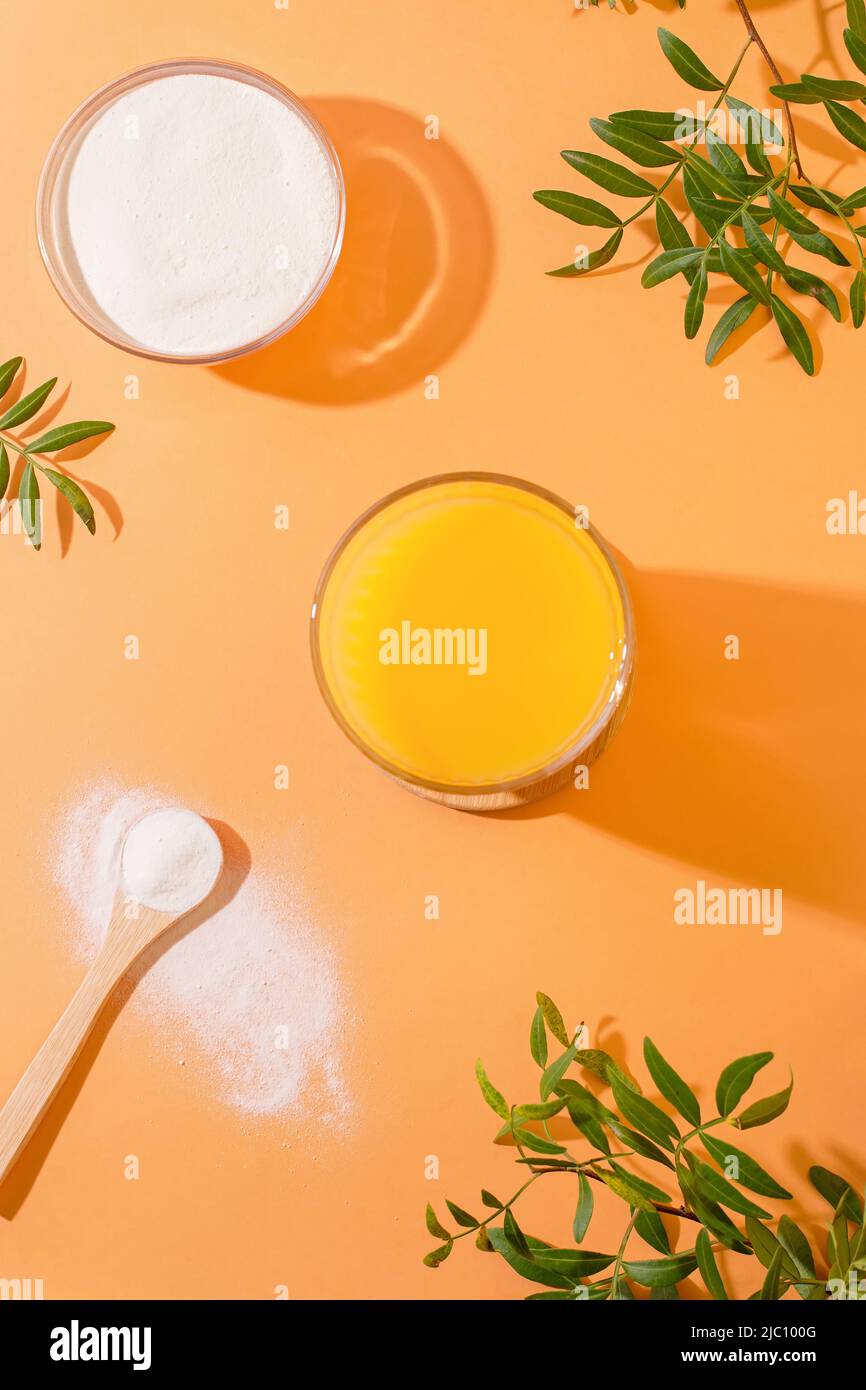 Orange juice glass and collagen powder on table with plant in hard ...