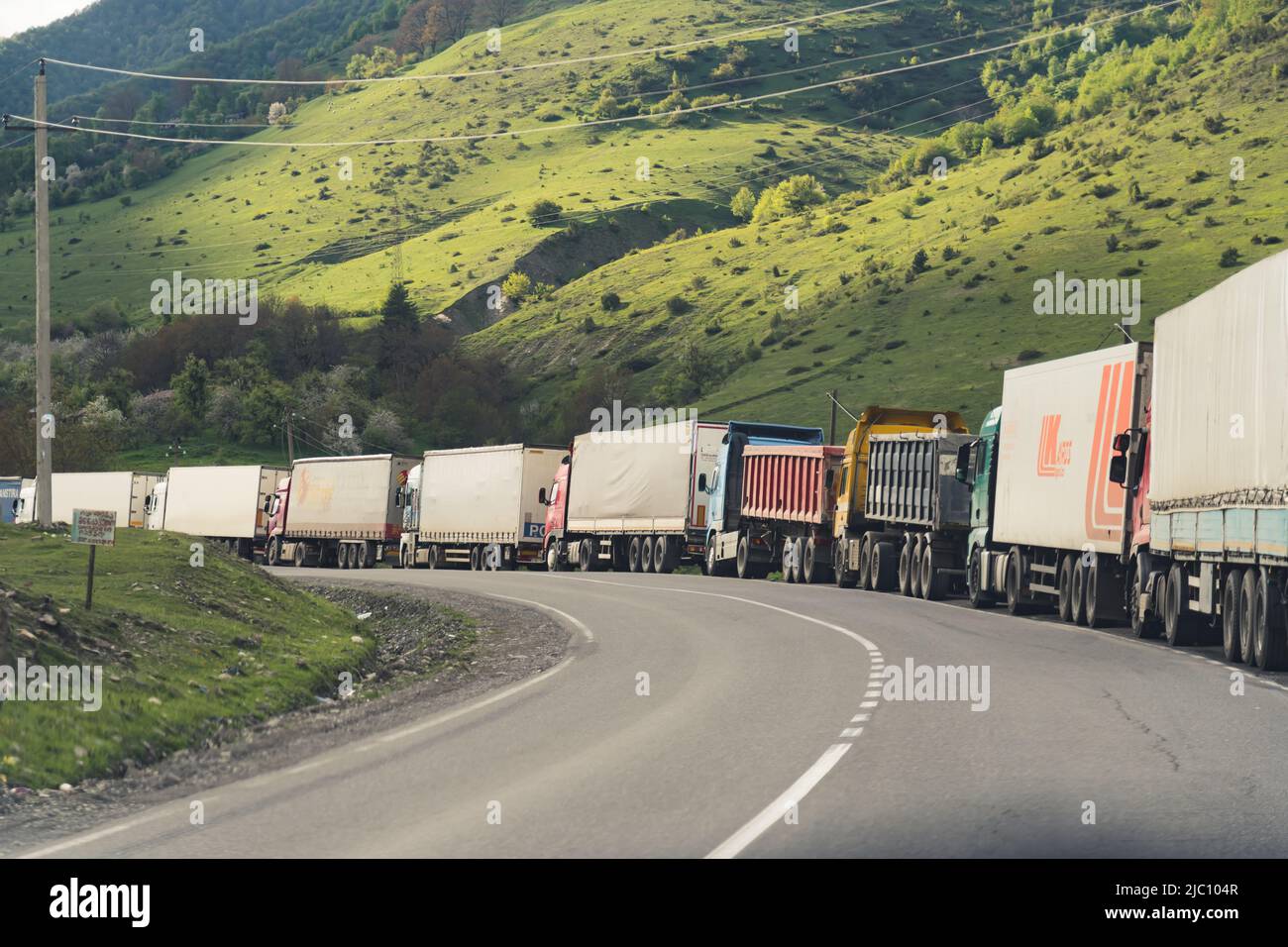Long queue of trucks delivering products standing over picturesque ...