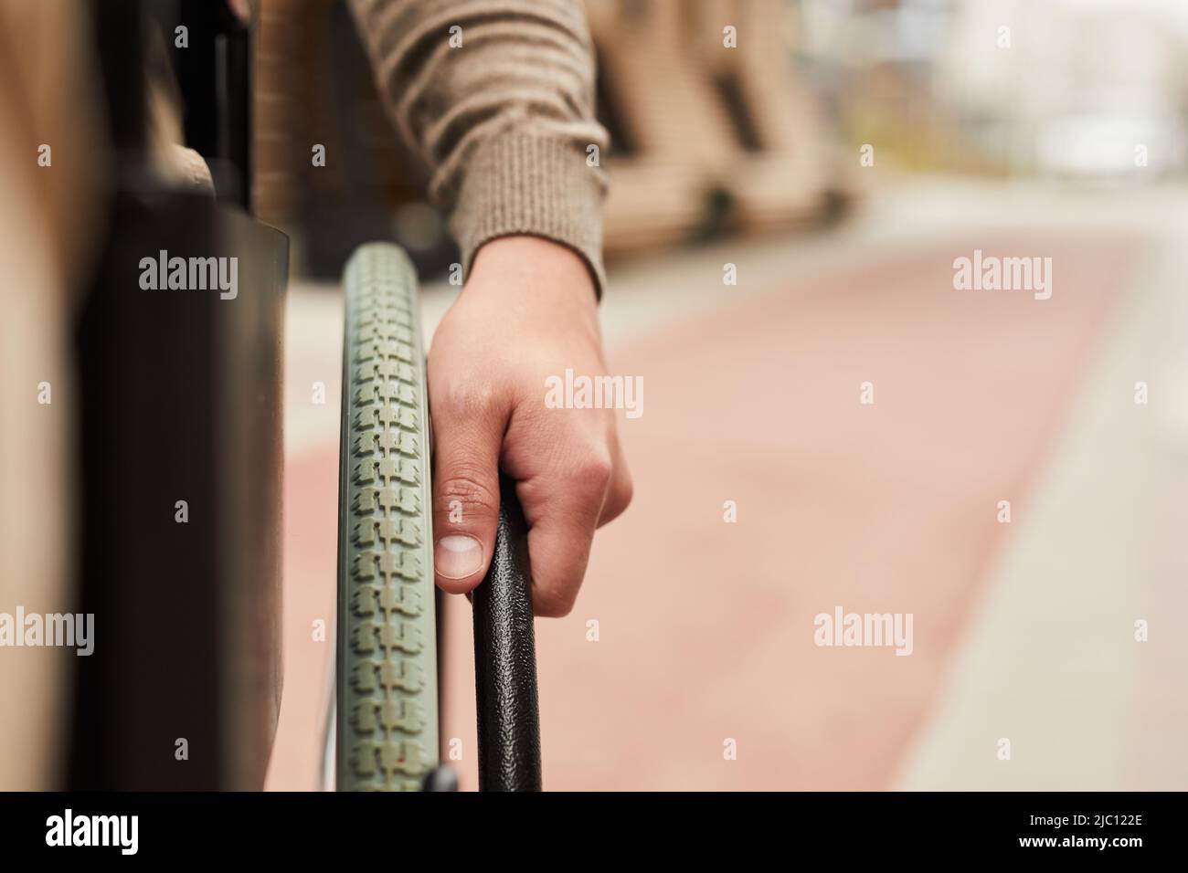 Close-up of unrecognizable man in sweater learning to use wheelchair ...