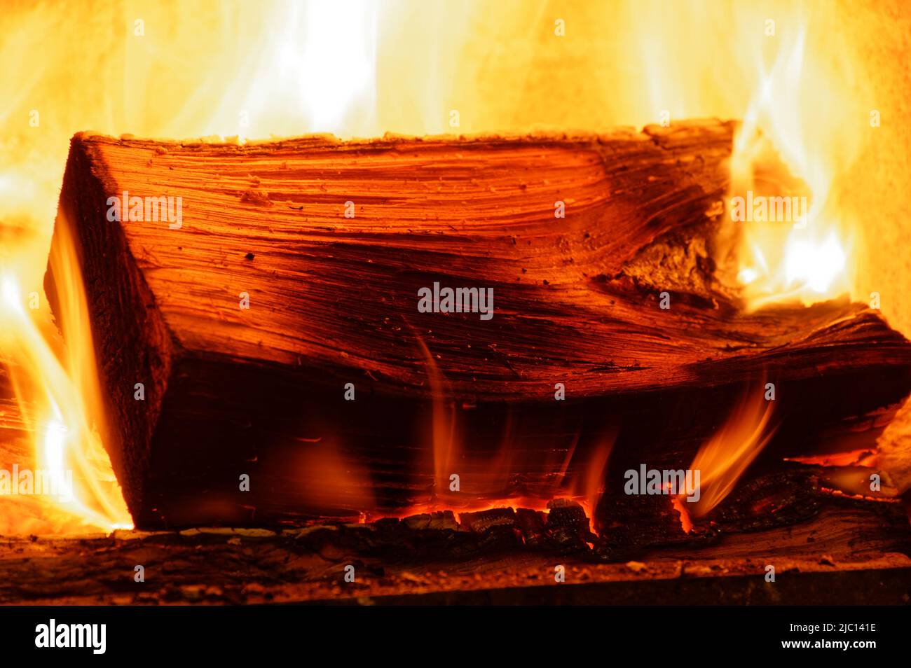 Flames lick around the base of a block of wood on an open fire, flames ...