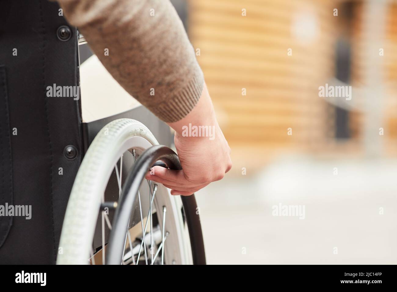 Close-up of unrecognizable man sitting in modern wheelchair and holding ...