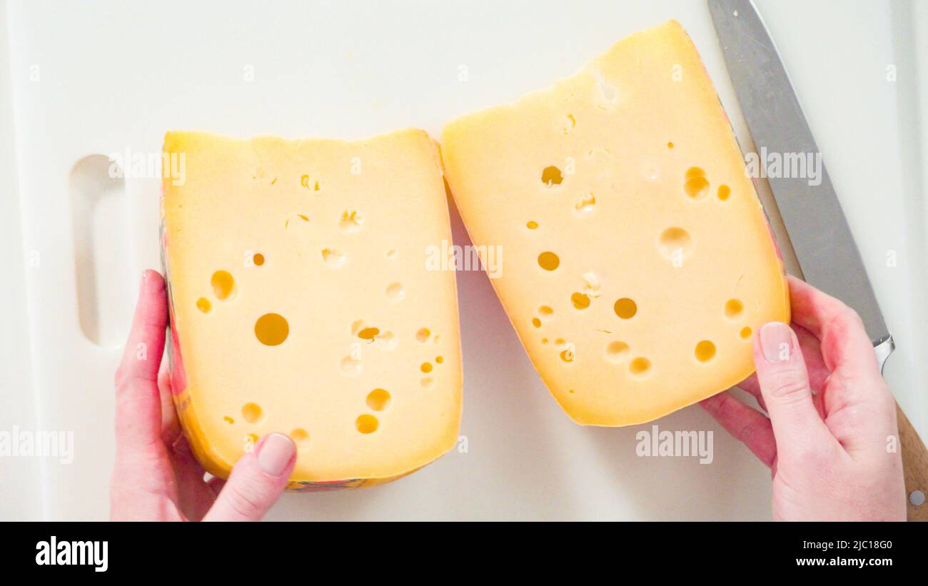 Flat lay. Slicing a large slice of gourmet cheese on a white background ...