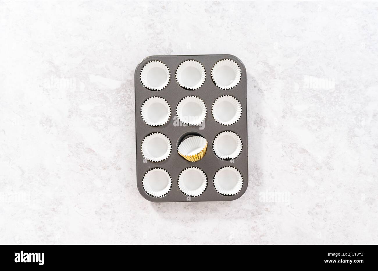 Flat lay. Lining cupcake baking pan with foil cupcake liners to bake ...