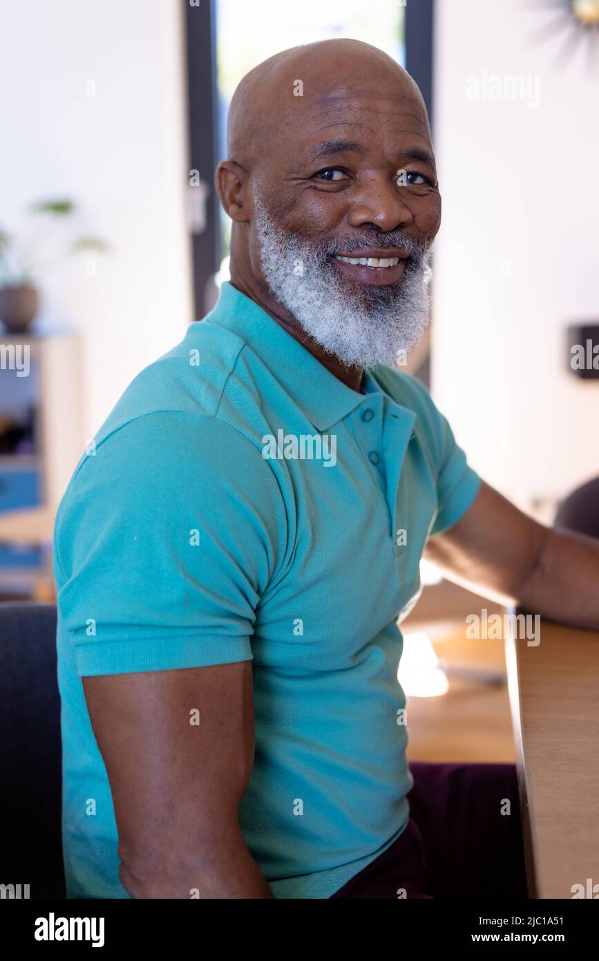 Portrait of smiling african american bald senior man sitting at dining ...