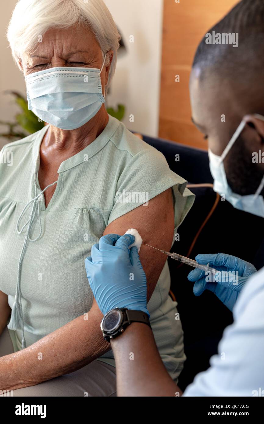 African american male health worker giving an injection to caucasian ...