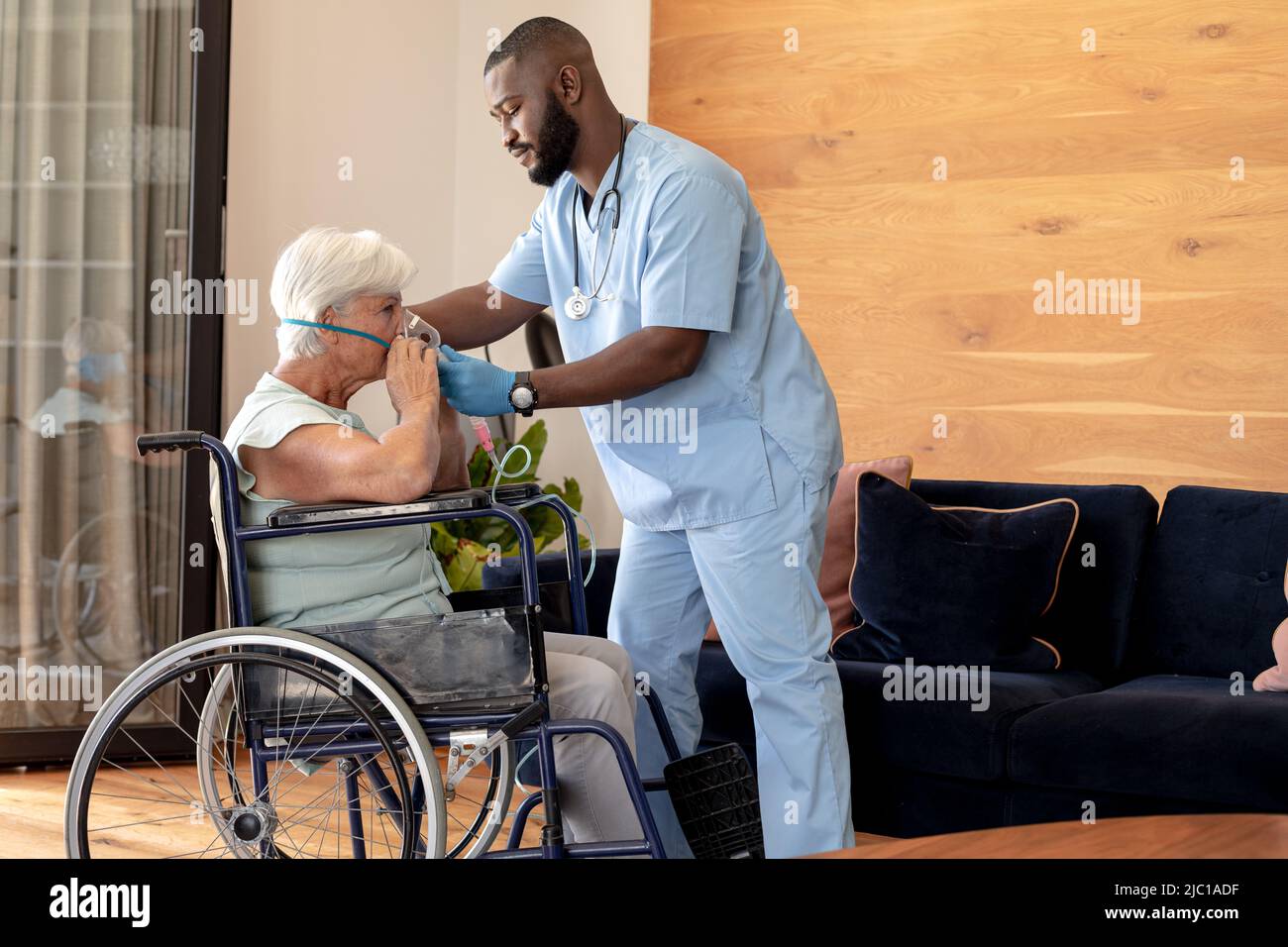 African american male health worker putting oxygen mask on caucasian ...