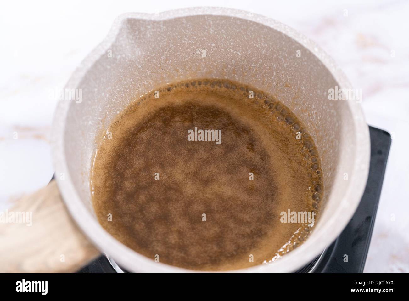 Cooking caramel glaze for bundt cake in a small saucepan over an ...