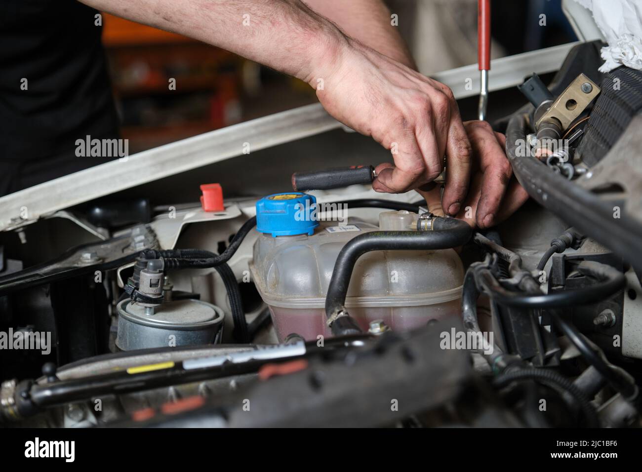 Car mechanic hands replacing antifreeze container Stock Photo - Alamy