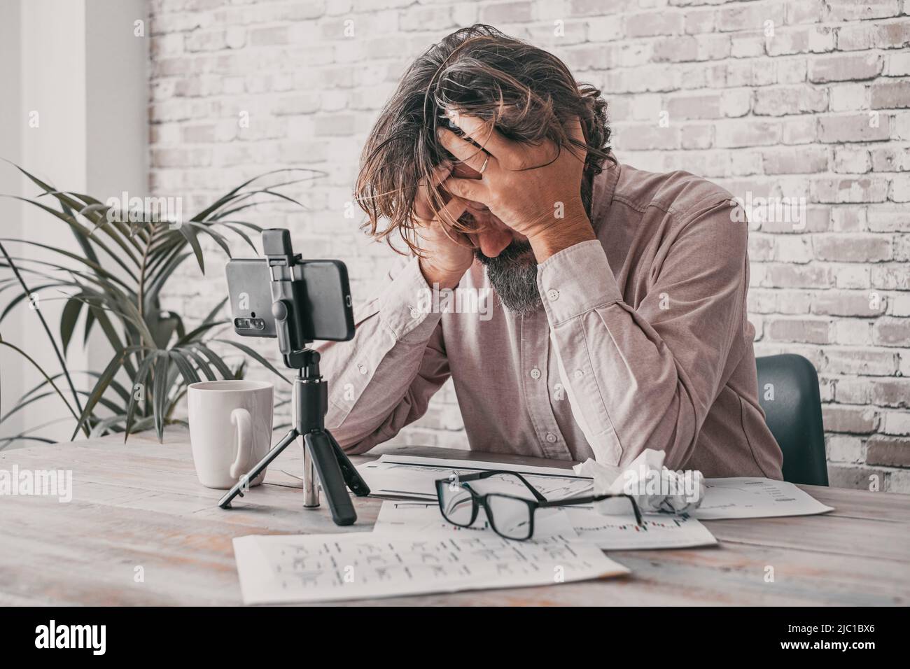 Man working at home on the table with desperate expression and posture ...