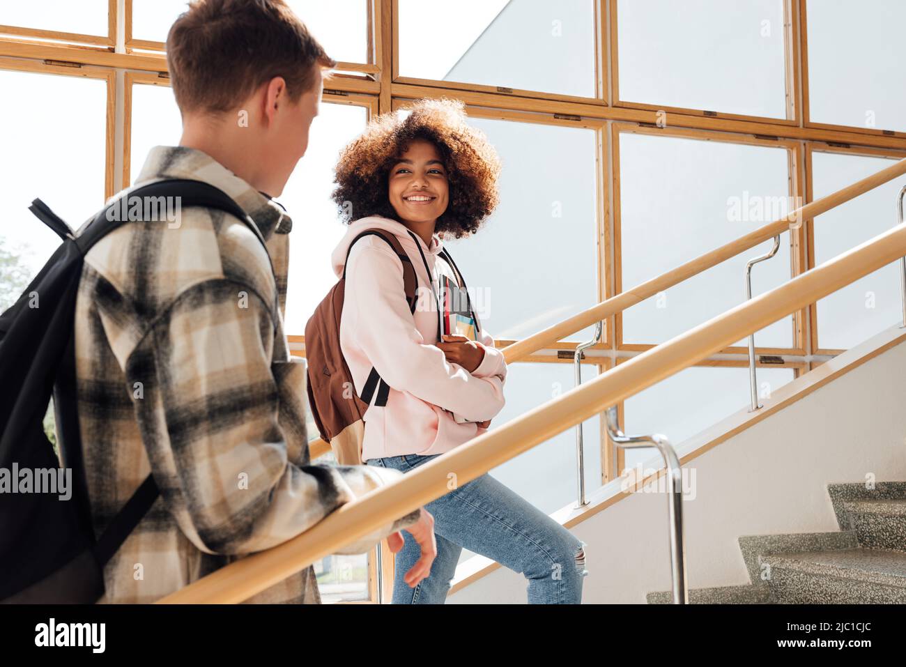 Two classmates climbing college stairs. Smiling woman student looking ...