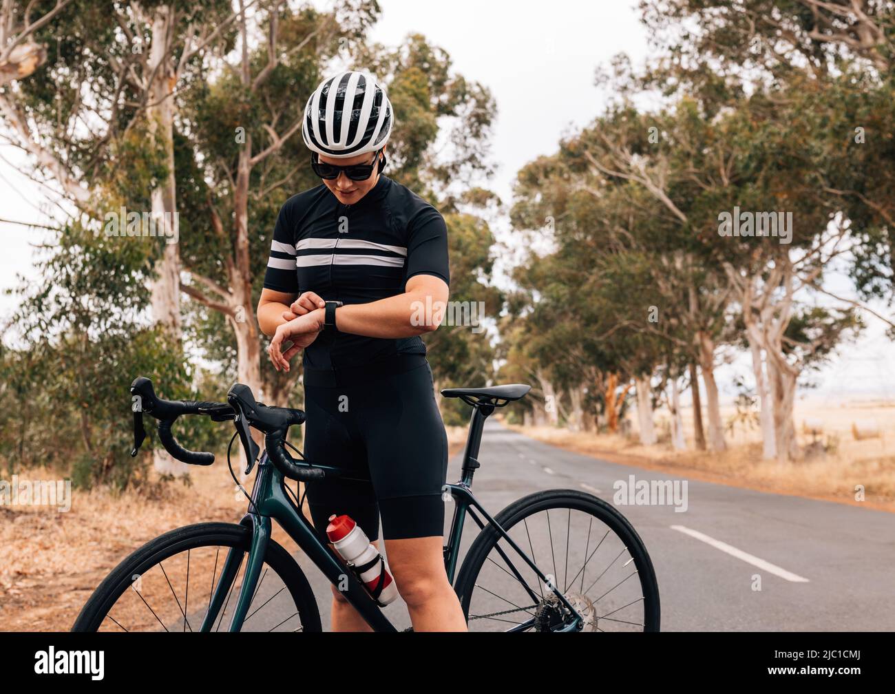 Professional woman cyclist standing with her bike on empty road ...