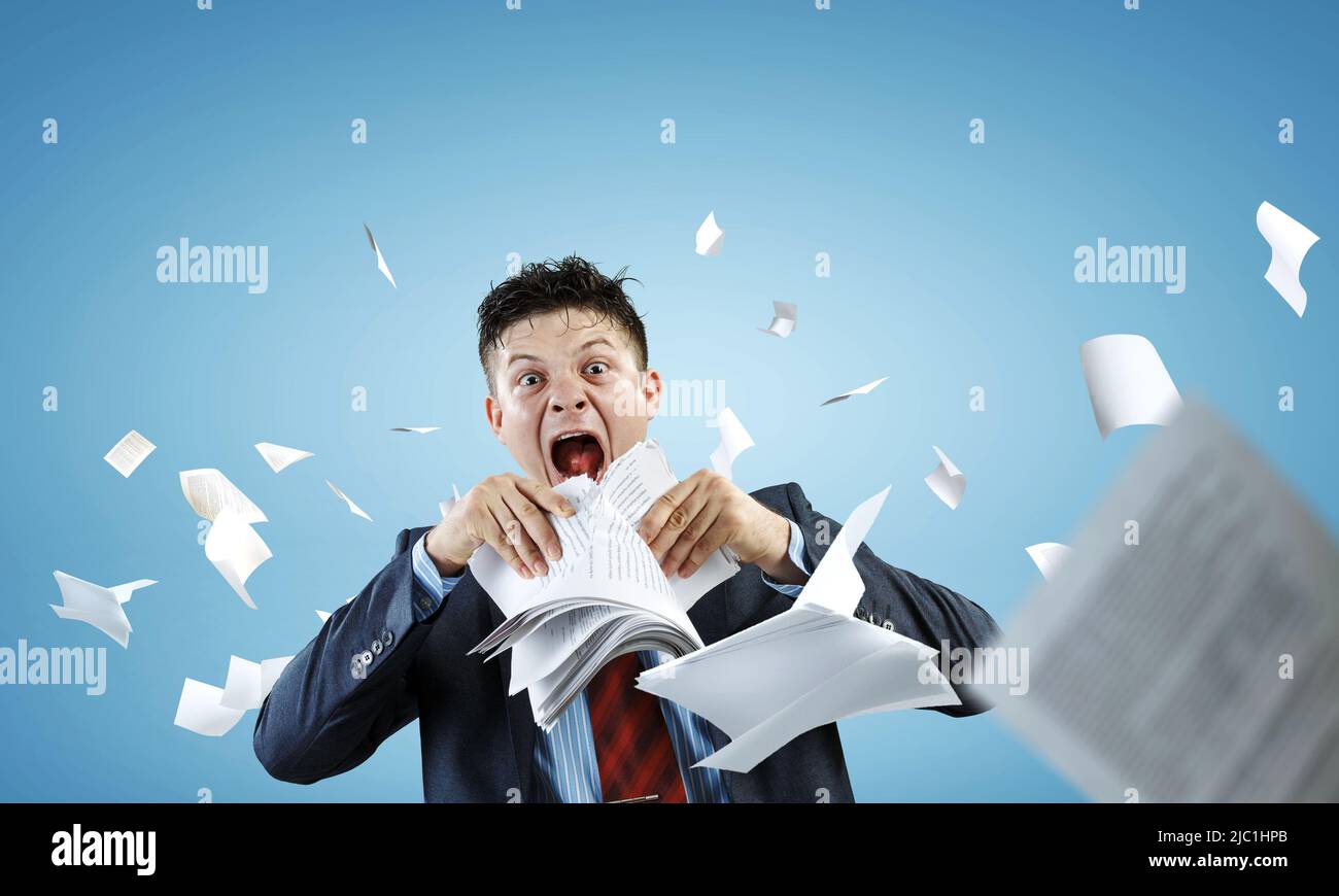 Young stressed man ripping documents with frustrated facial expression ...