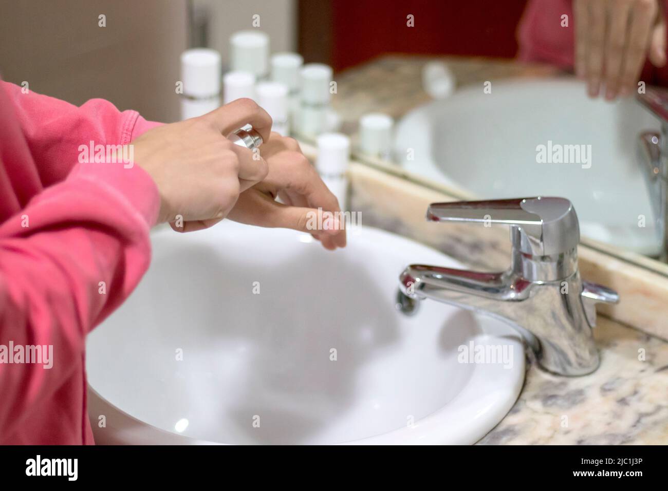 Girl spraying perfume on hands in the bathroom Stock Photo - Alamy