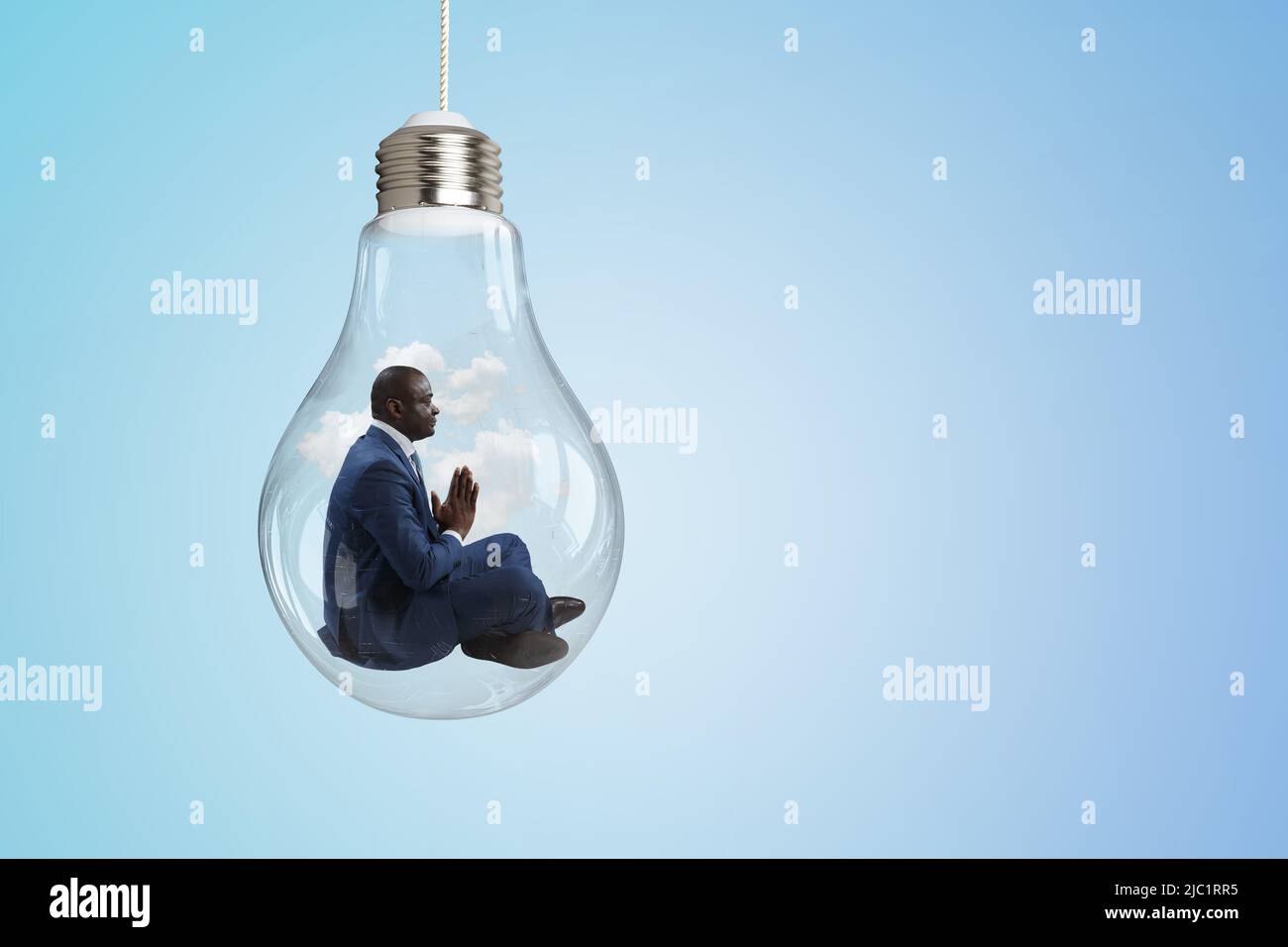 Young black man sitting and meditating inside light bulb Stock Photo ...