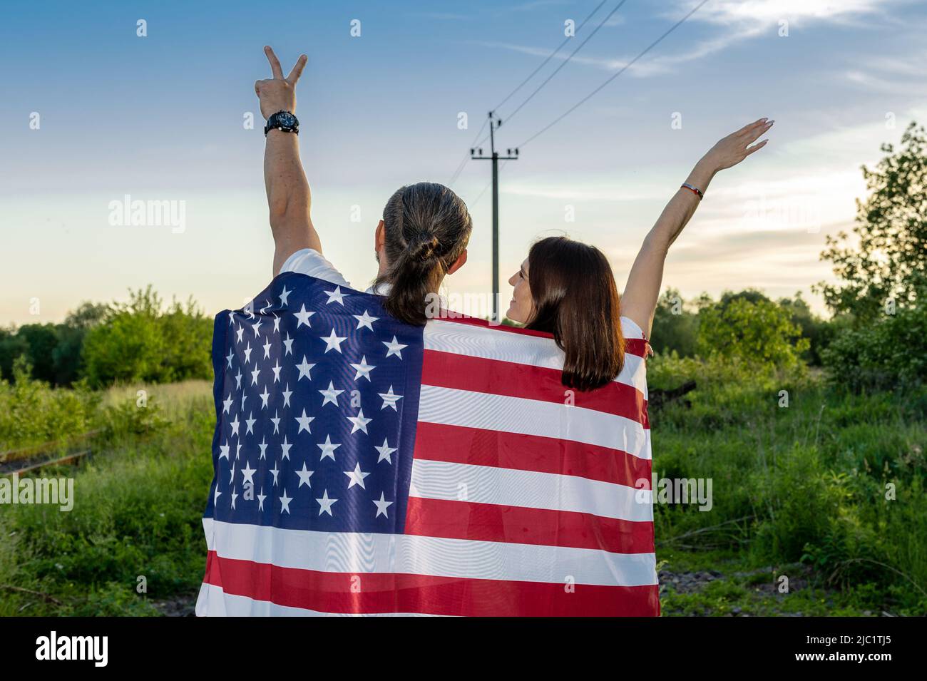 Back view of man and woman holding american flag outdoor Stock Photo ...