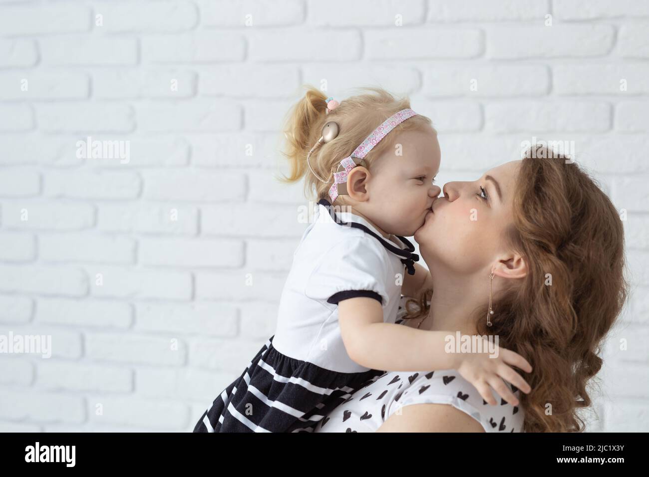 Mother holds and having fun child with hearing aids and cochlear ...