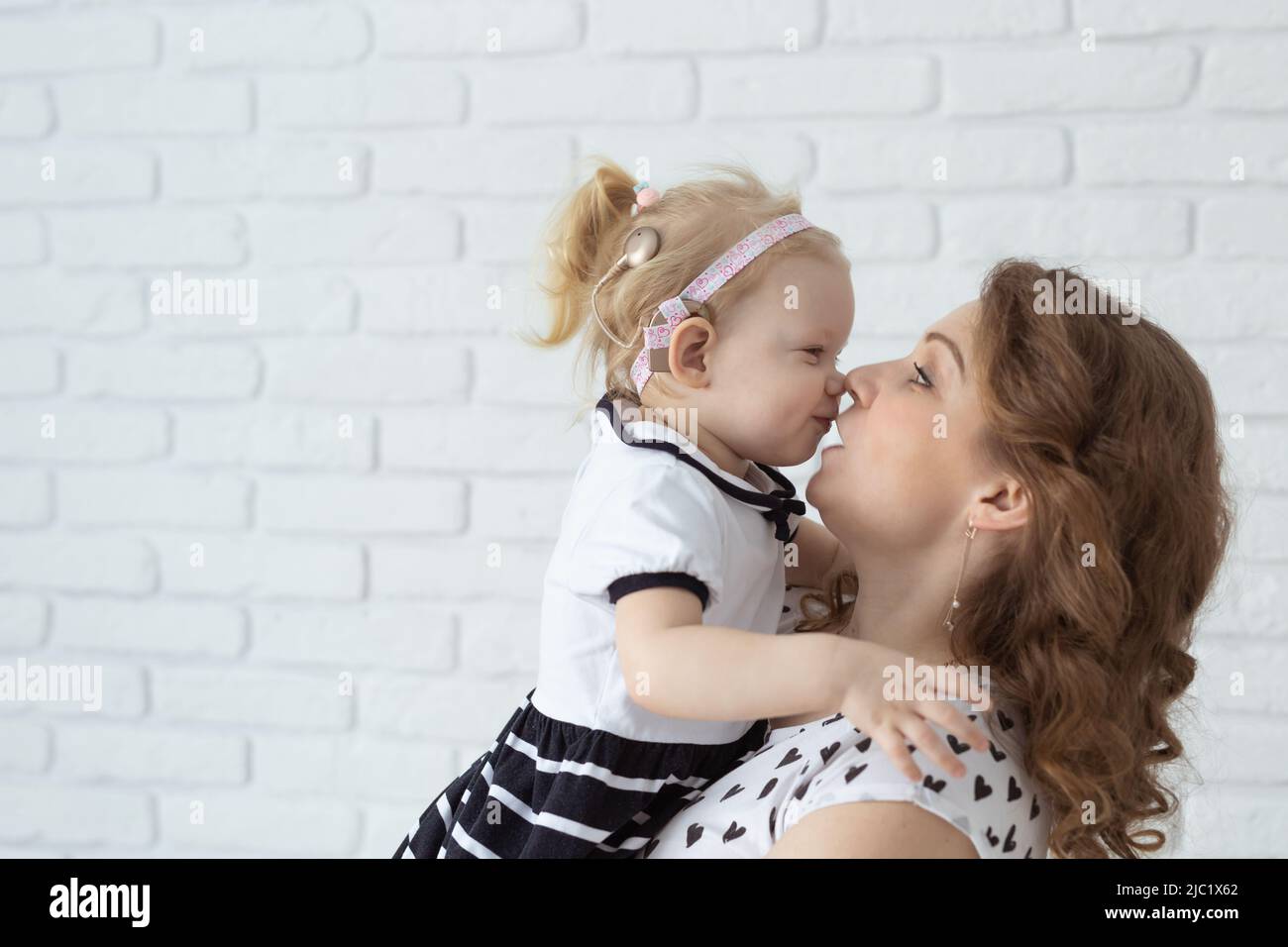 Mother holds and having fun child with hearing aids and cochlear ...