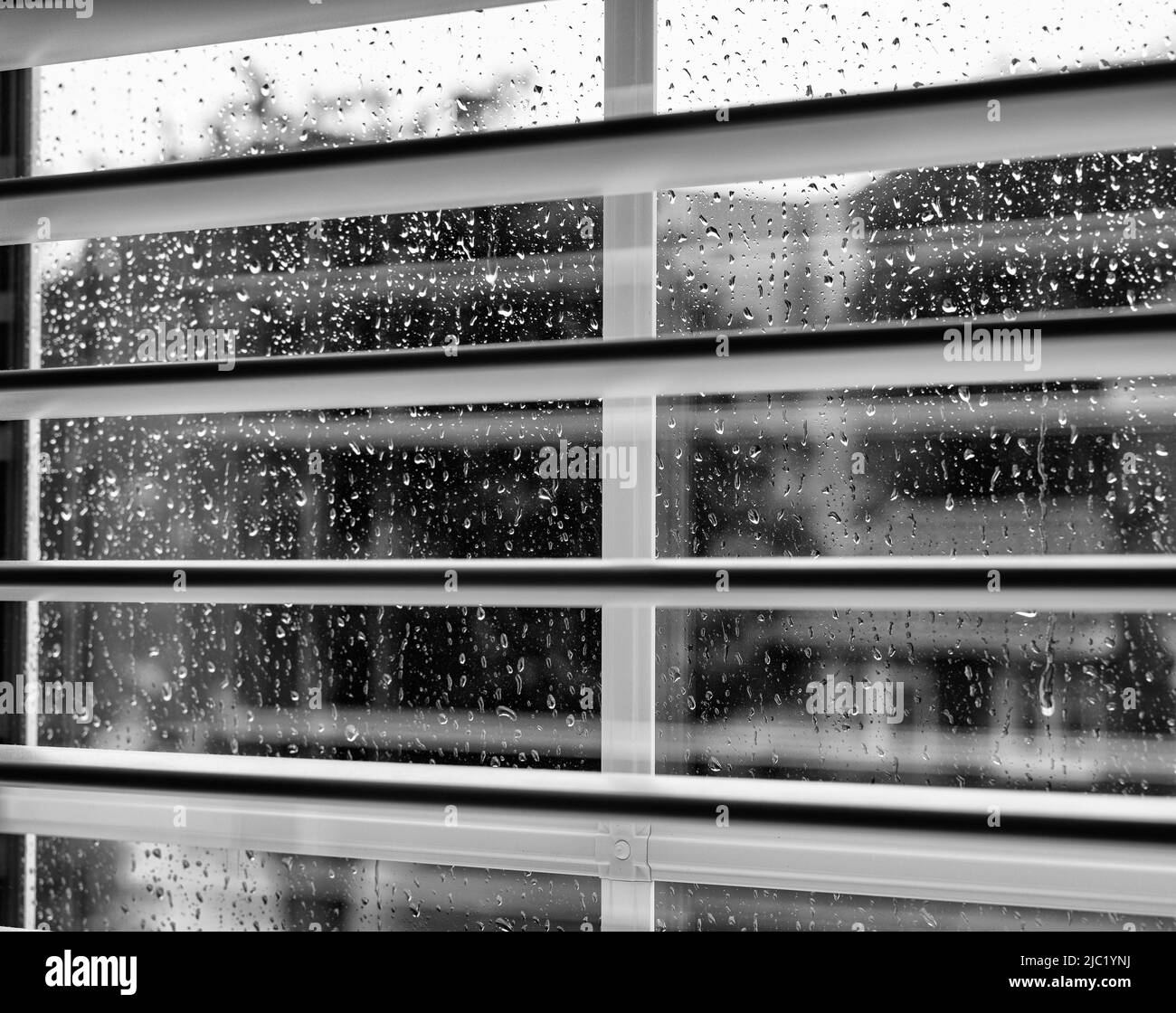 Looking through window shutters onto rain soaked double glazed windows ...