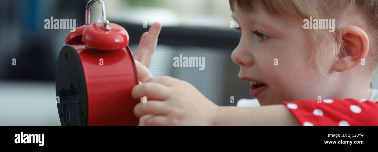 Curious little pretty girl explore red clock touch dial with finger ...