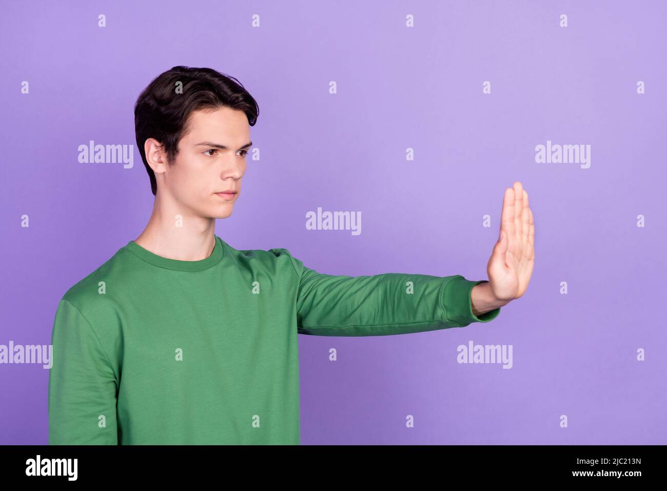 Profile side photo of young guy look empty space hold hand stop sign ...