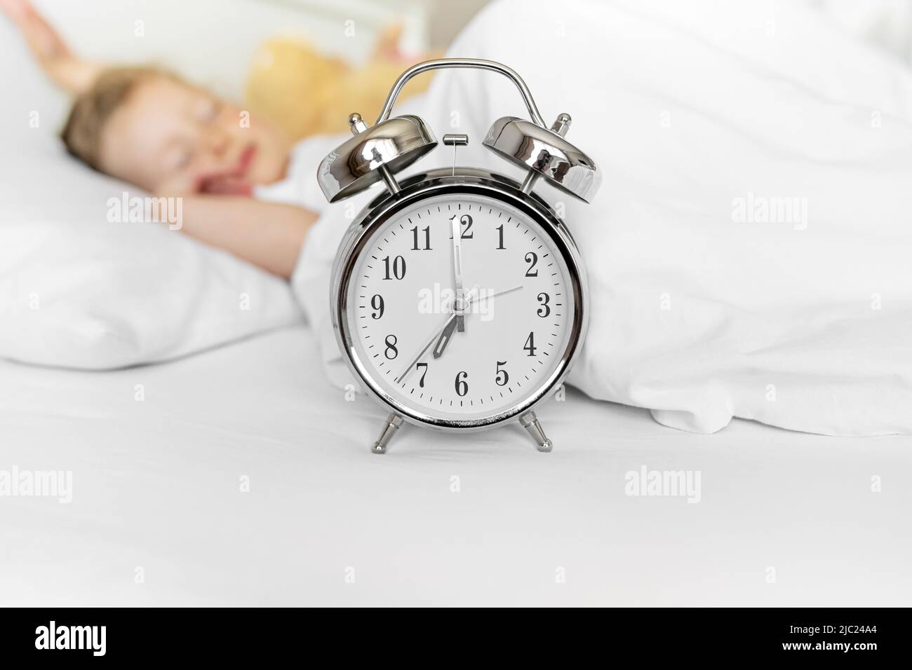 Alarm clock on the background of a sleeping child Stock Photo - Alamy