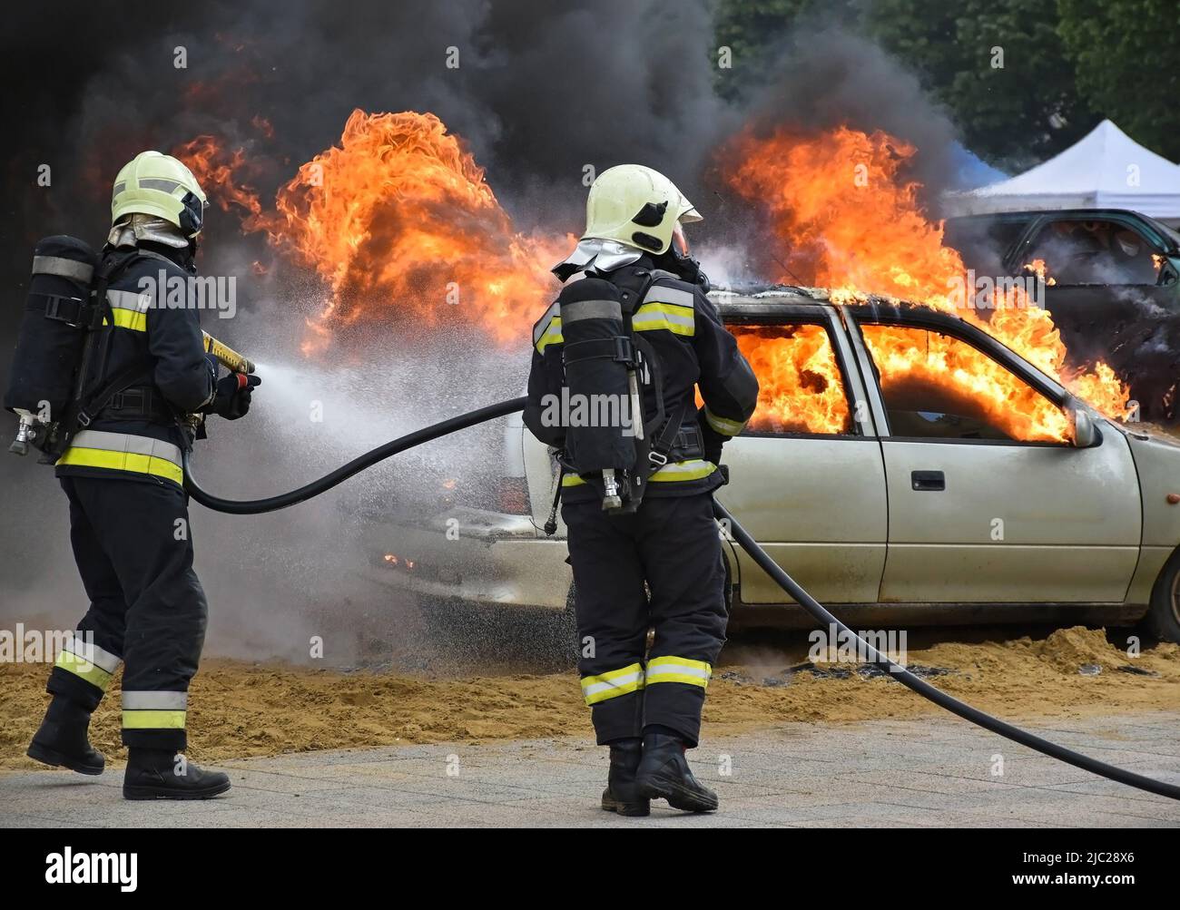 Firefighters at work next to a burning car Stock Photo - Alamy