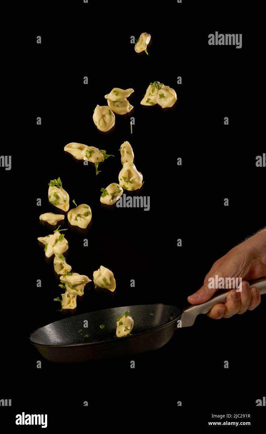 Anonymous chef tossing delicious traditional dumplings with herbs in ...