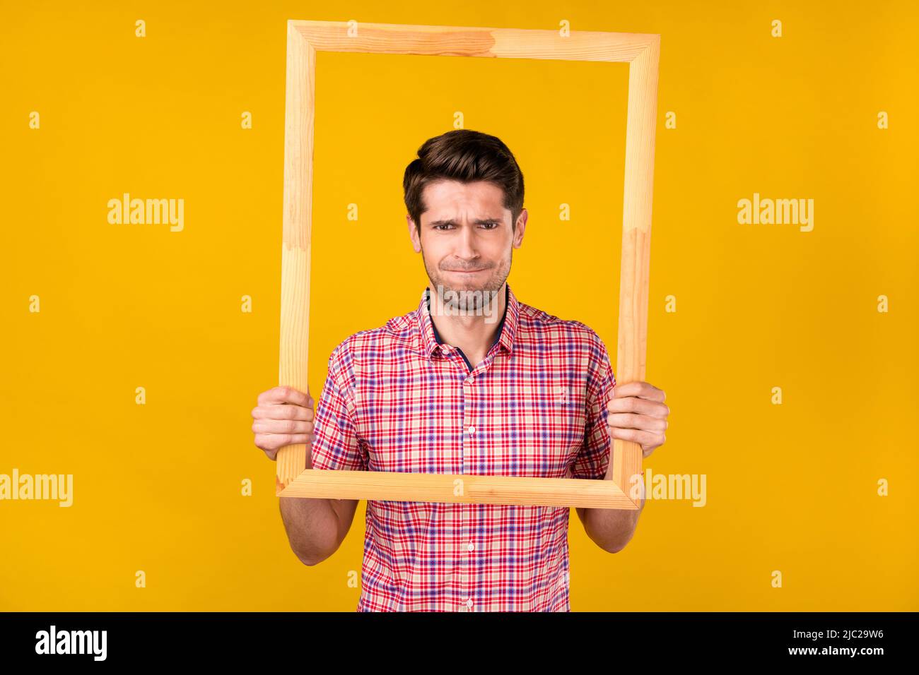 Portrait of attractive nervous guy holding in hands frame posing ...
