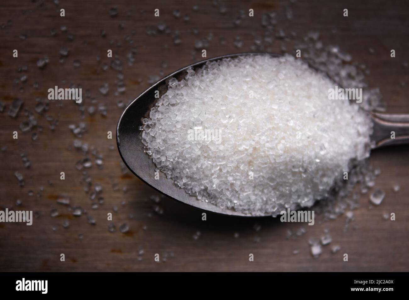 Granulated white cane sugar in a spoon. Cane sugar over metallic ...