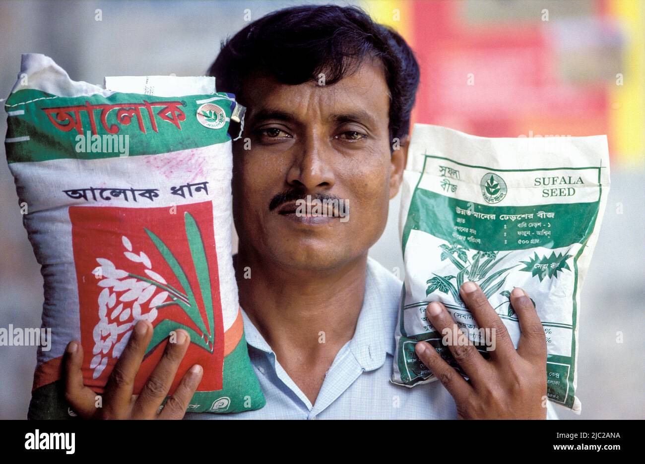 Bangladesh; retailer showing pack of rice and pack of seeds Stock Photo ...