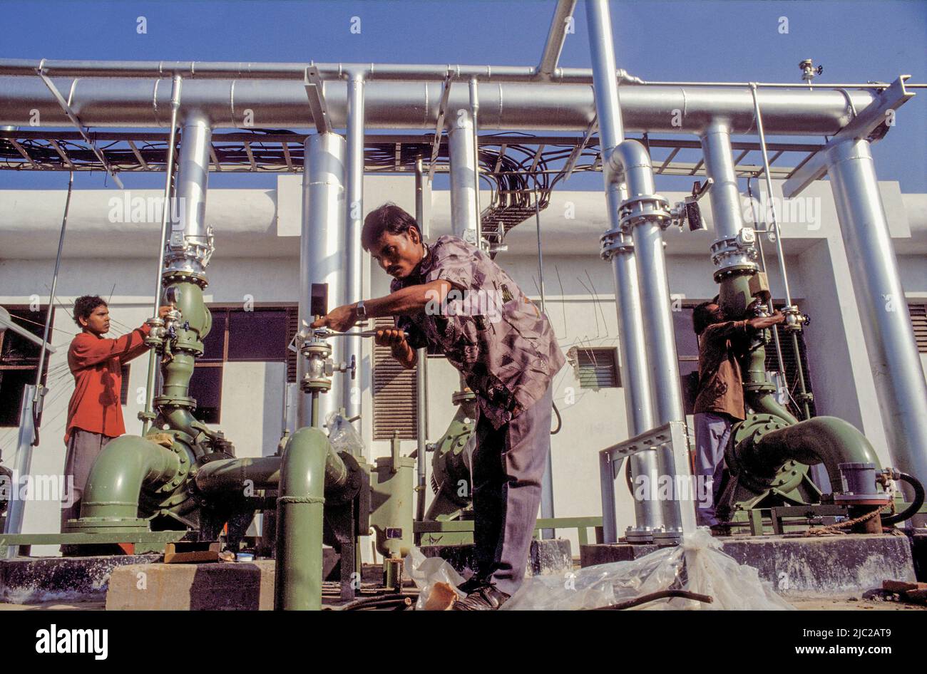Bangladesh; workers at machines on the exterior of the textile factory ...