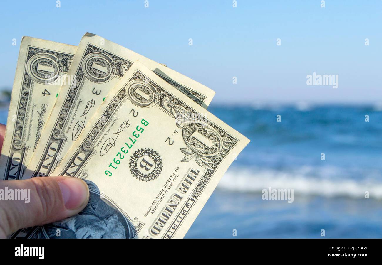 Person holds in his hand three dollar bills on the background of the ...