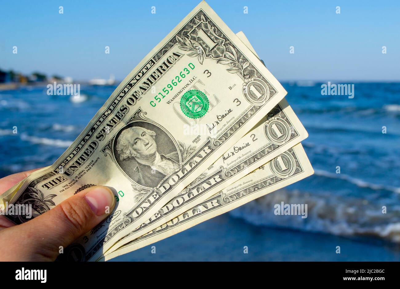Person holds in his hand three dollar bills on the background of the ...