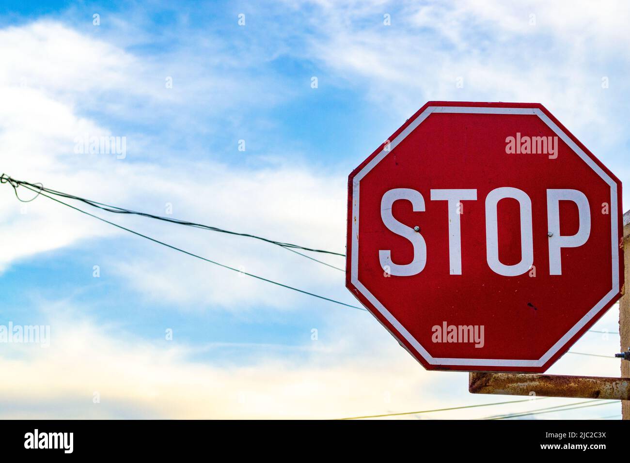 Image of a road traffic stop sign against blue sky and cloud background ...