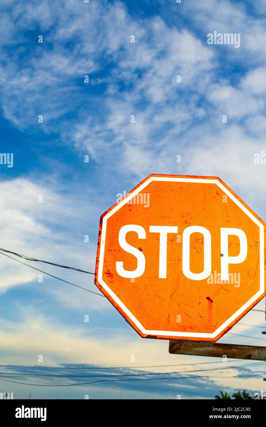 Image of a road traffic stop sign against blue sky and cloud background ...