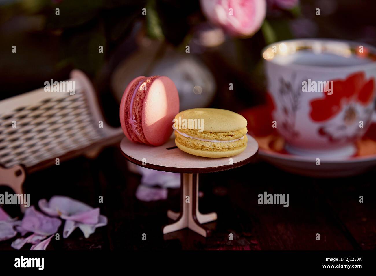 French macarons on the wooden miniature table near bench in cafe style ...