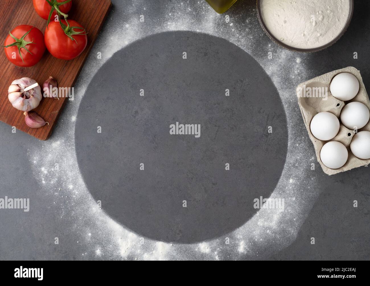 Empty pizza space with tomatoes, eggs and flour over stone background ...