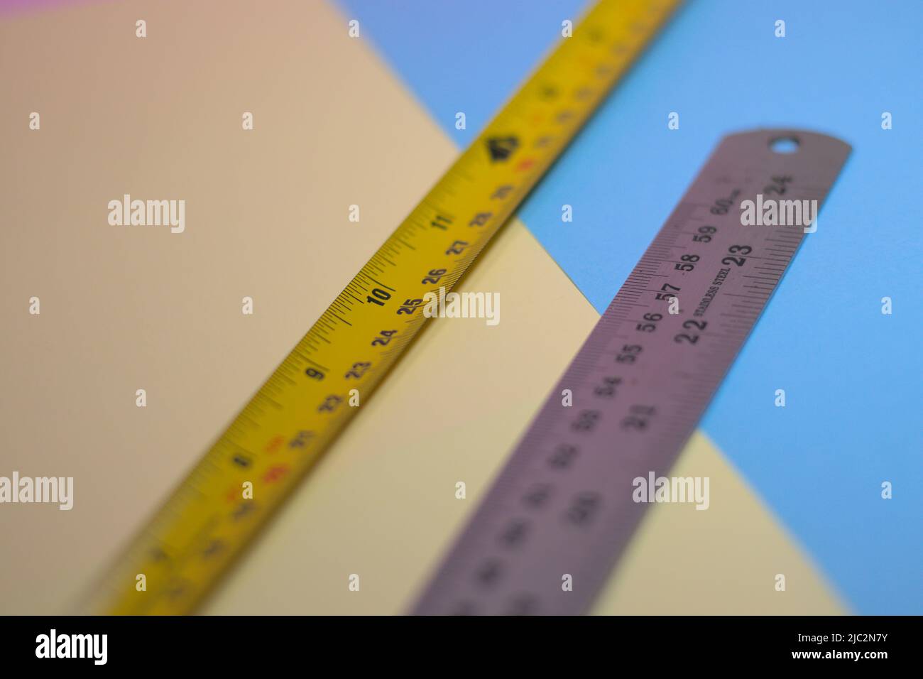 Yellow measuring tape and stainless steel ruler on blue and yellow ...