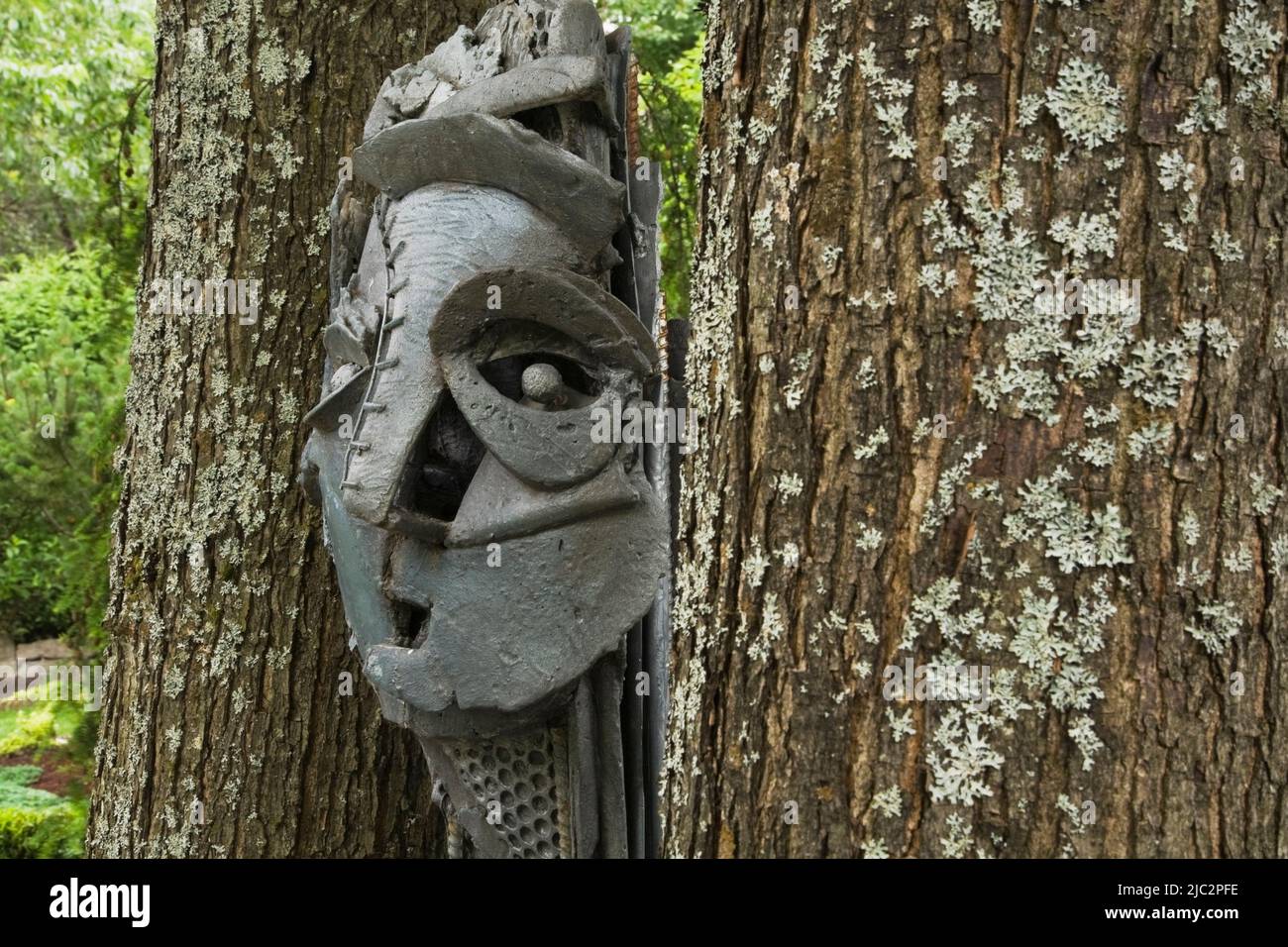 Close-up of sculpture between two trees in border in landscaped ...