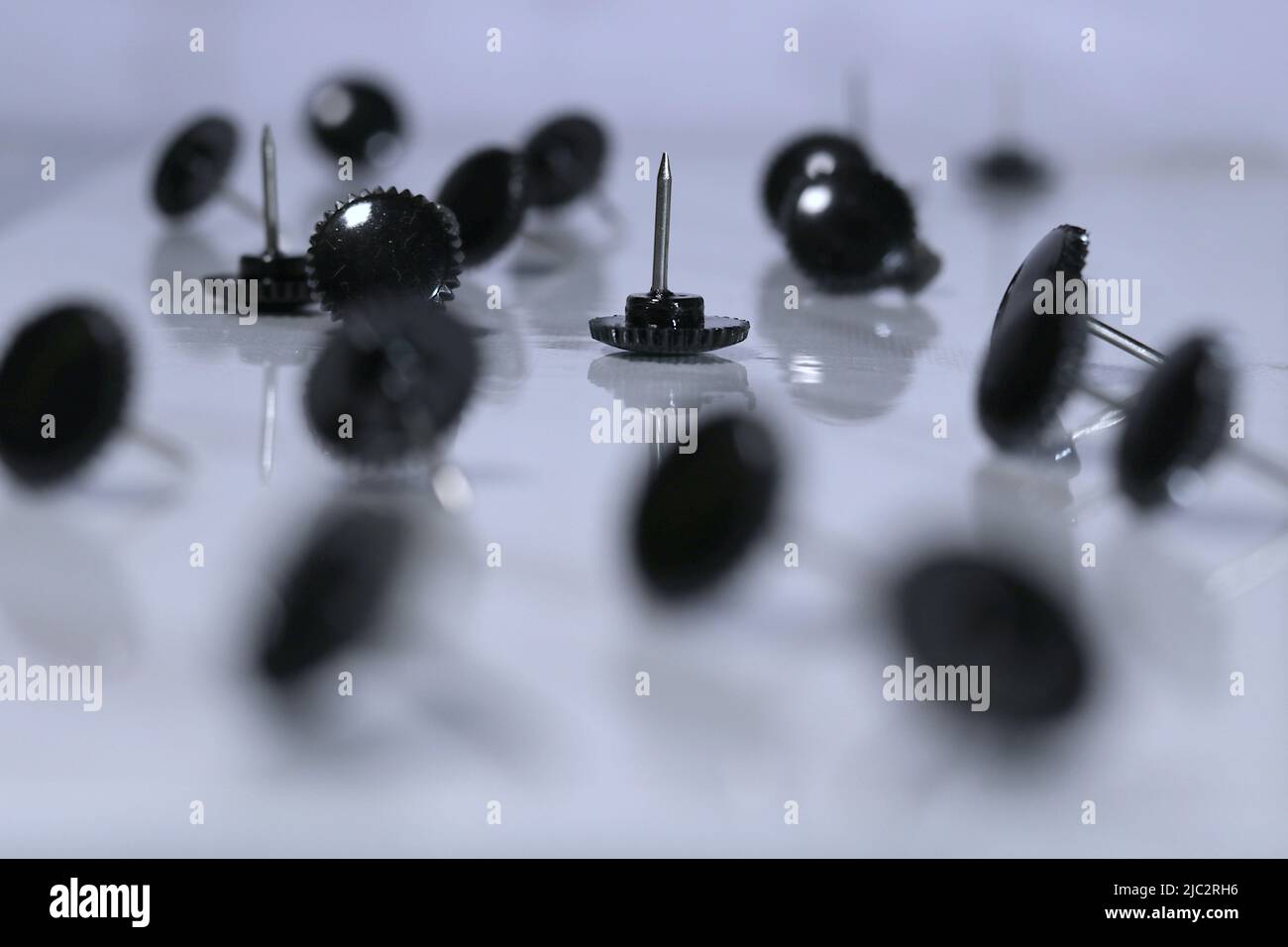 Scattered black push pins on white surface Stock Photo - Alamy