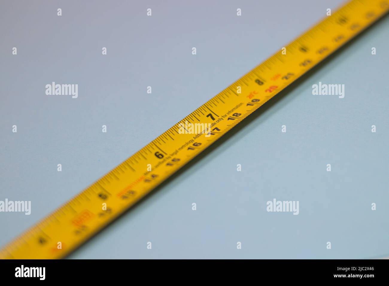 Yellow measuring tape on blue surface Stock Photo - Alamy