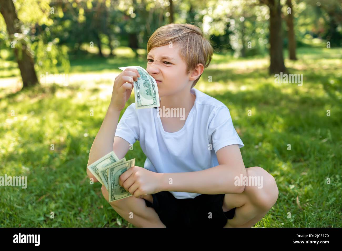 the boy holds dollar bills, one of which he brought to his nose and ...