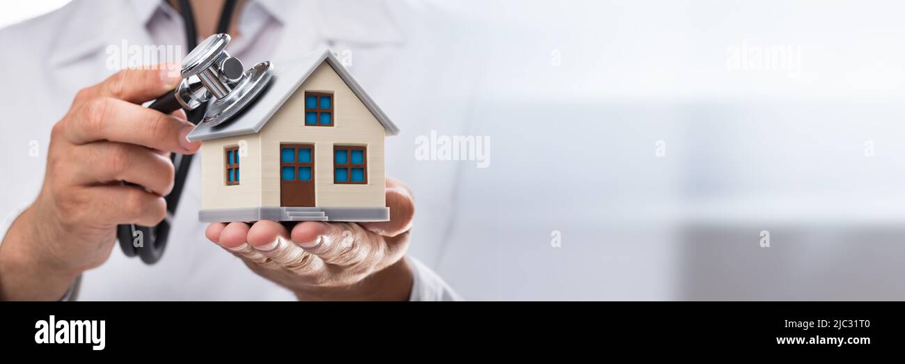Close-up of a doctor's hand examining house model with stethoscope ...